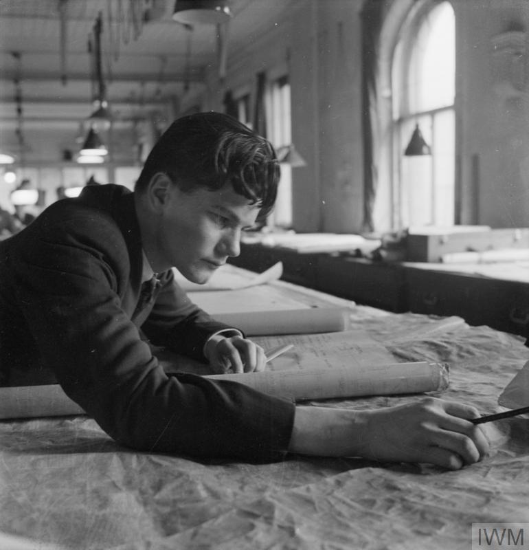 A close-up of a young man working on plans in the drawing office ...